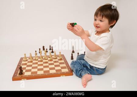 Toddler baby playing chess, studio white background. A child with chess ...