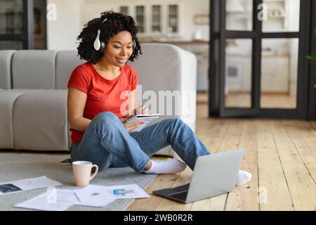 Focused Young Woman Writing In Notebook At Home Office With Laptop ...