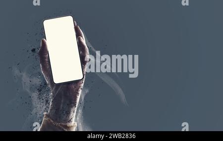 Creepy zombie hand holding a smartphone with blank screen, horror and ...