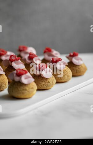 Eclair Choux with pink raspberry cream on a white marble board Stock ...