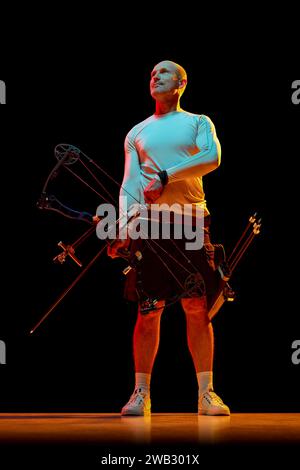 Full-length image of man, archer standing with archery bow and arrows ...