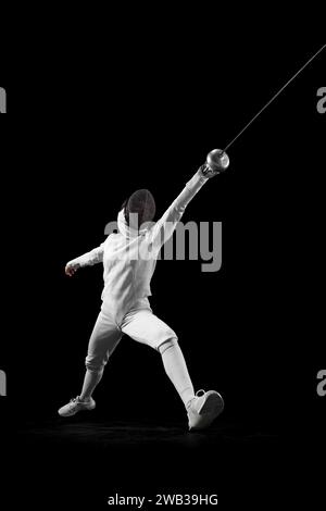 Fencer lunges forward, her blade in motion against black studio ...