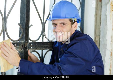 workman using sandpaper on metal window shutters Stock Photo - Alamy