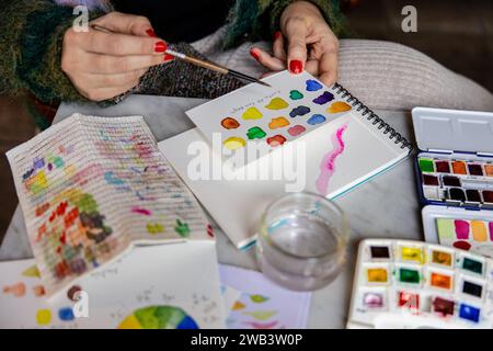Detail of woman's hands with artistic painting material and color chart ...
