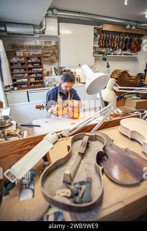 A musical instrument master in his workshop demonstrating a base for a ...