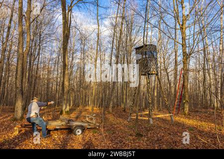 Man preventing a homemade deer hunting stand from toppling over as it's ...