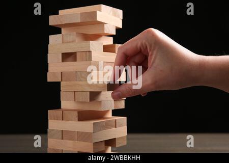 Woman playing Jenga at table against black background, closeup Stock ...