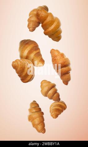 Golden croissants falling on beige gradient background Stock Photo - Alamy