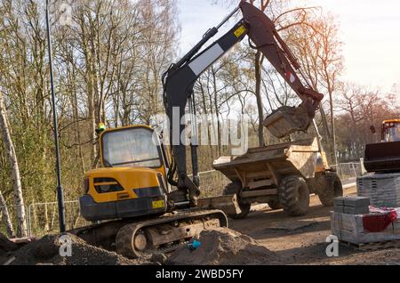 Excavator loading semi-dry concrete mix into dumper on construction ...