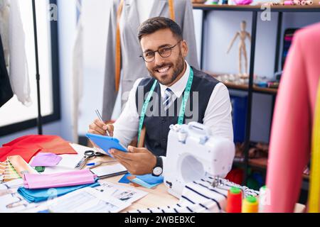 Young hispanic man tailor drawing on touchpad at tailor shop Stock ...