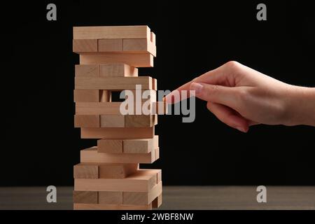 Woman playing Jenga at table against black background, closeup Stock ...