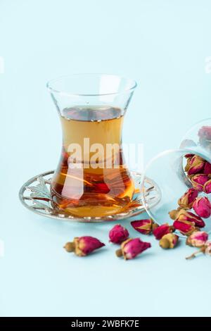 Glass of Turkish tea and dry roses on light blue background Stock Photo ...