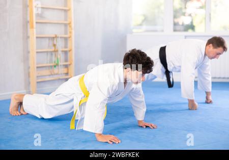 Boy and coach doing muscle stretching before boxing or judo class ...