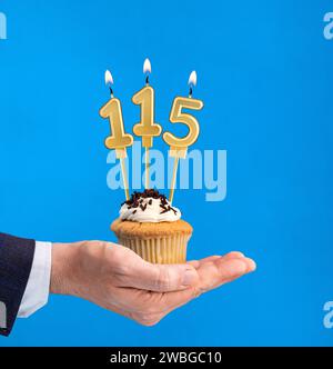 Number 115 candle with birthday cupcake on a red background with blue ...