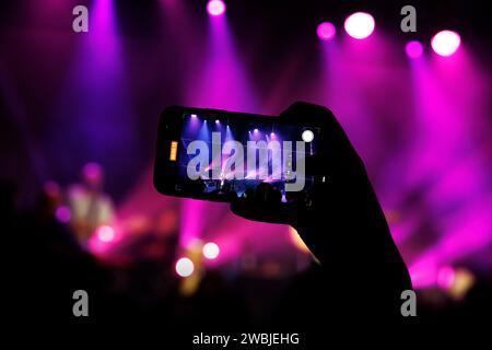 A concert-goer captures the live performance of a band on their phone ...