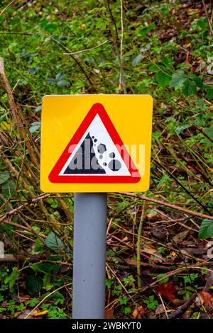 Warning sign with red triangle to indicate danger of falling rocks in a ...