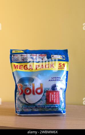 Laundry detergent capsules and clothes in washing machine drum, closeup ...