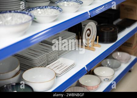 Various ceramic Asian dinnerware displayed on shelves in store Stock ...