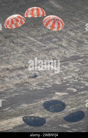 Orion’s three main orange and white parachutes help a representative ...