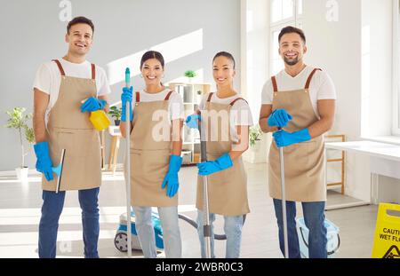 Happy janitors in uniform from professional cleaning service looking at ...
