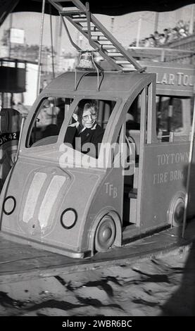 1960s, historical, outside at a funfair, a young women standing playing ...