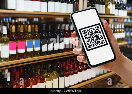 Consumer in Wine Shop scanning data matrix QR code on label of wine ...