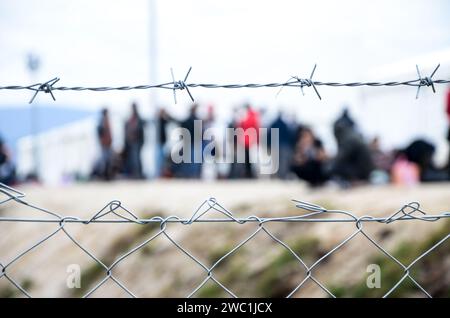 Barbed wire in refugee camp. Migrants behind chain link fence in camp ...