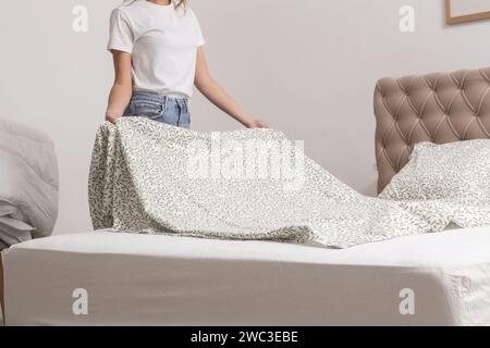 Woman changing bed linens at home in her bedroom, cozy domestic ...