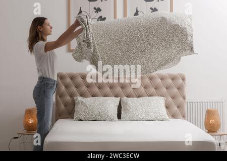 Woman changing bed linens at home in her bedroom, cozy domestic ...