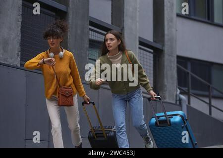 Being late. Worried women with suitcases running outdoors Stock Photo ...