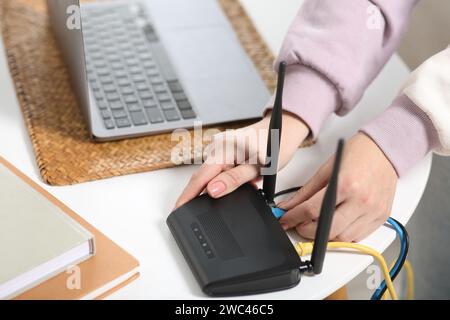 Woman connecting cable to Wi-Fi router at table indoors, closeup Stock ...