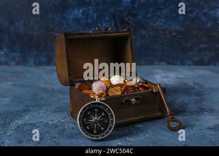Old chest with treasures, key and compass on grunge blue background ...