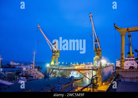 Industrial shipyard at dusk, floating dry dock with ship under repair ...