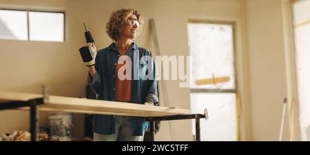 happy woman using hand drill to assemble a table Stock Photo - Alamy