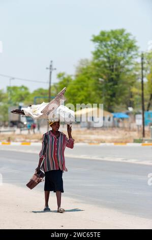 African woman carrying scrap metal on her head through the streets ...