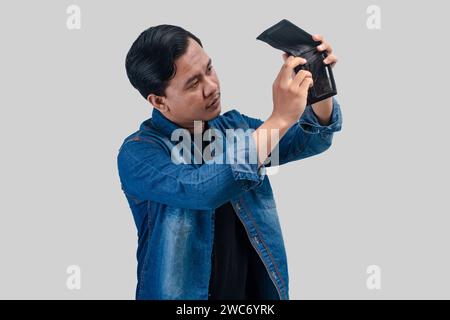 Young Asian man showing sad face expression while holding his empty ...