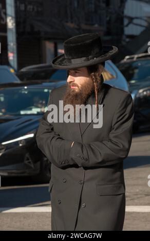 A Hasidic Jewish man walks on Lee Ave. while speaking on his flip phone ...
