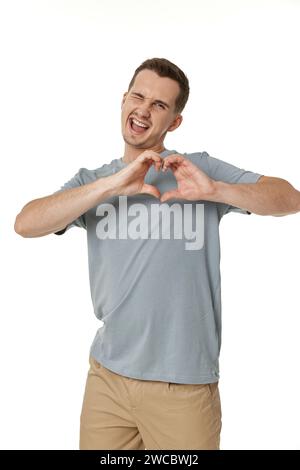 Young hispanic couple doing heart symbol with hands sitting on the bed ...