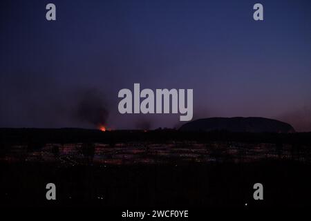 Uluru Australia in silhouette, fire & smoke on the horizon, Field of ...