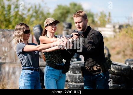 Girls learn to shoot pistols at targets at a shooting range with an ...