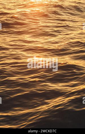 Golden sunlight reflecting on rippling water in a smooth, abstract ...