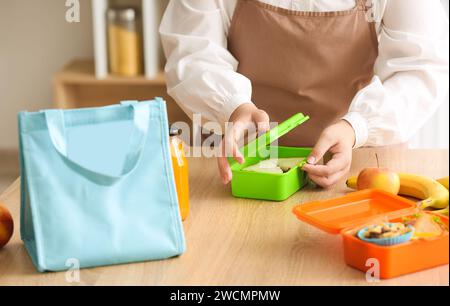 Mother packing meal in lunchbox for school on table at kitchen Stock ...