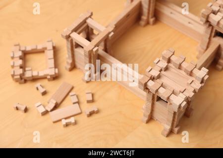 Wooden fortress and building blocks on table against grey background ...