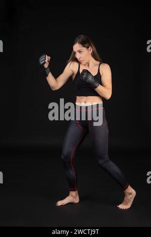 Athletic female MMA fighter training over blue-pink background in neon ...