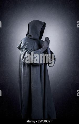 Medieval monk in hooded cloak praying in the dark Stock Photo - Alamy