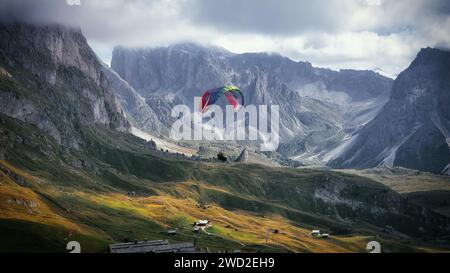 Paraglider in flight on the side of Mount Seceda in Dolomites, Italy ...