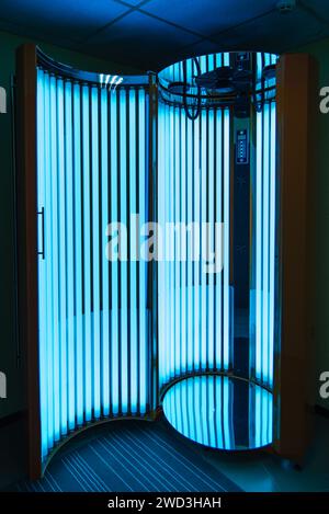 vertical Solarium with glowing blue light ultraviolet lamps for tanning ...