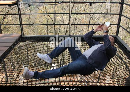 Latin adult man uses his cell phone in an armchair in a room makes ...