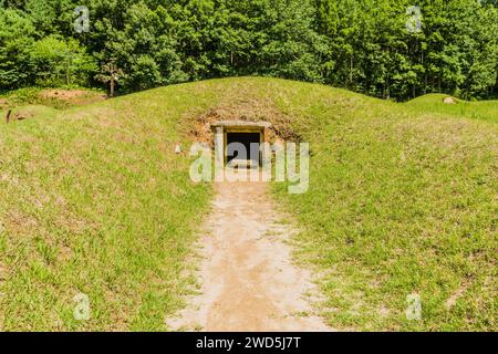 Unmarked mound tomb with dirt path leading to concrete opening on dry ...