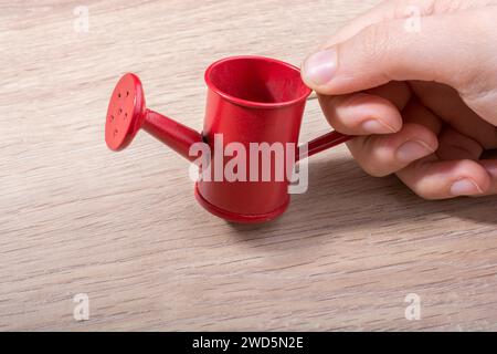 Little red color watering can in hand Stock Photo - Alamy